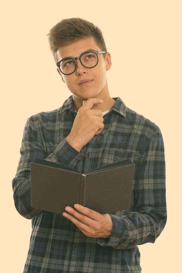 Studio Shot of Young Handsome Man Holding Book while Thinking Stock ...