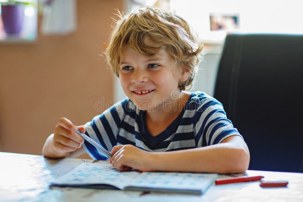 Portrait of Happy Boy Doing Homework in Kitchen at Home. Elementary School Studing Writing and ...
