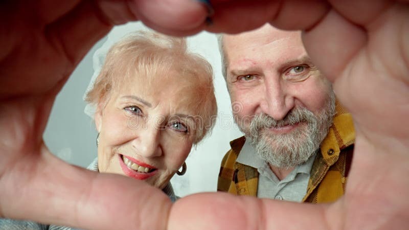 Portrait of a Happy Elderly Couple is Making Hand Heart, Looking at ...