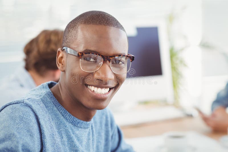 Portrait Of Happy Man Wearing Eyeglasses While Sitting At Desk Stock