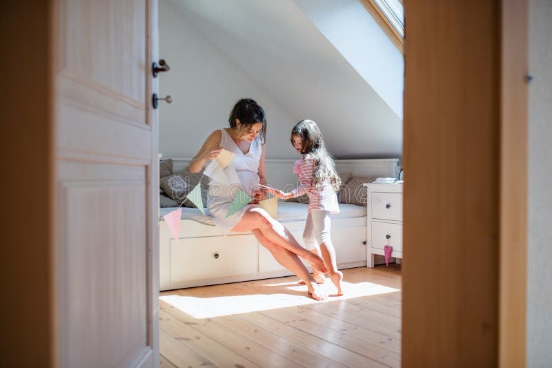 Portrait Of Pregnant Woman With Small Daughter Indoors At Home Playing