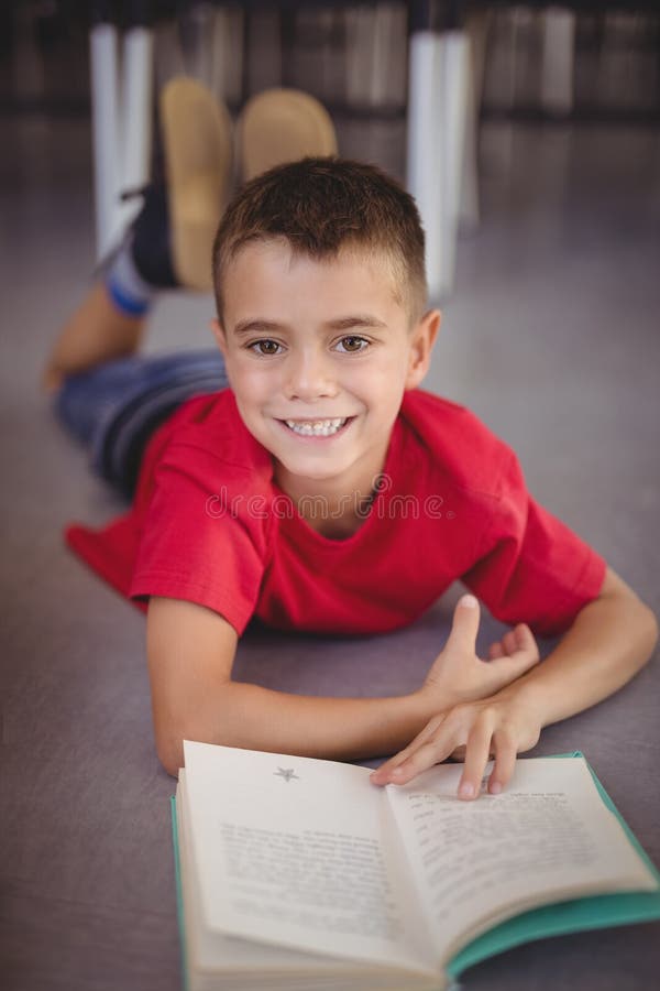 Portrait of Happy Schoolboy Reading Book in Library Stock Photo - Image ...