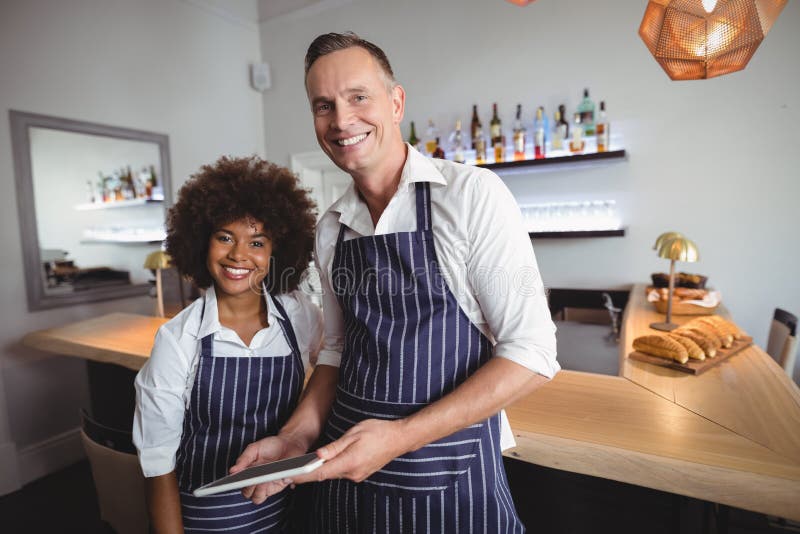 Portrait of Happy Waiter and Waitress Using Digital Tablet at Counter ...