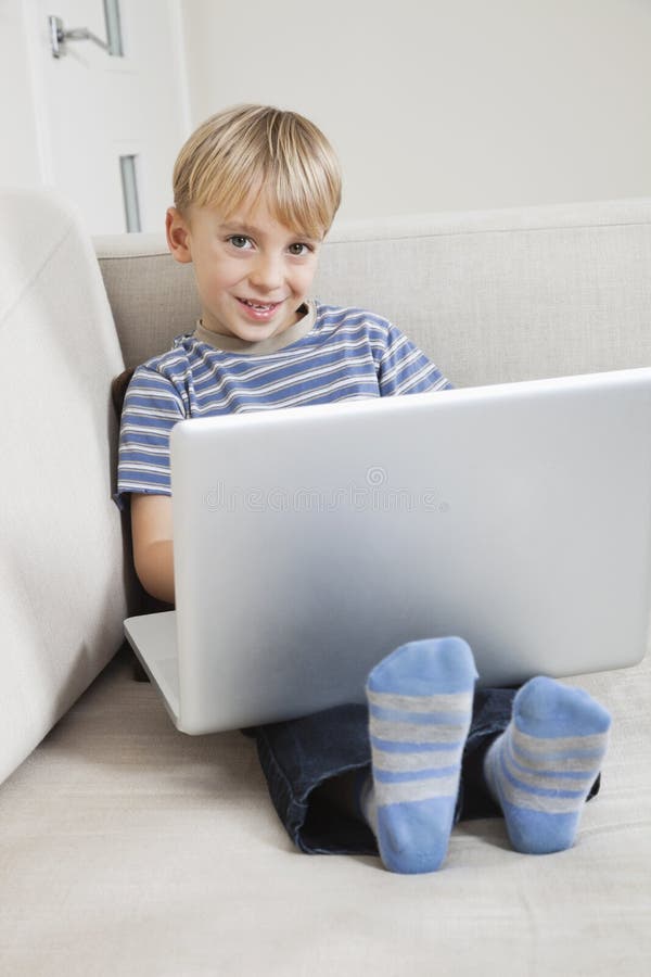 Portrait of Happy Young Boy Using Laptop on Sofa Stock Photo - Image of ...
