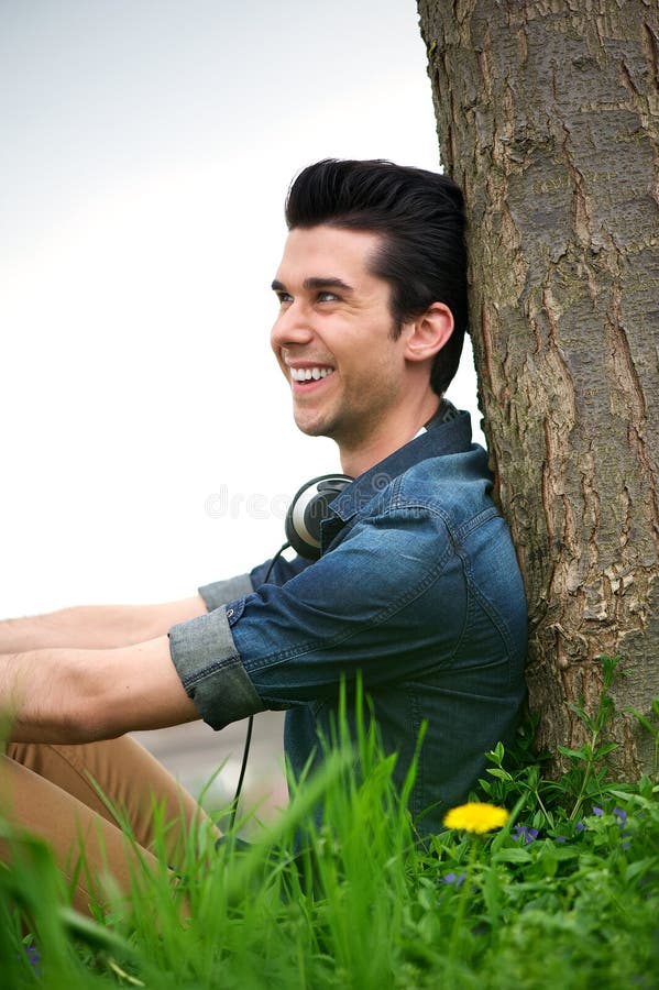 Portrait of a Happy Young Man Relaxing Against a Tree Outdoors Stock ...