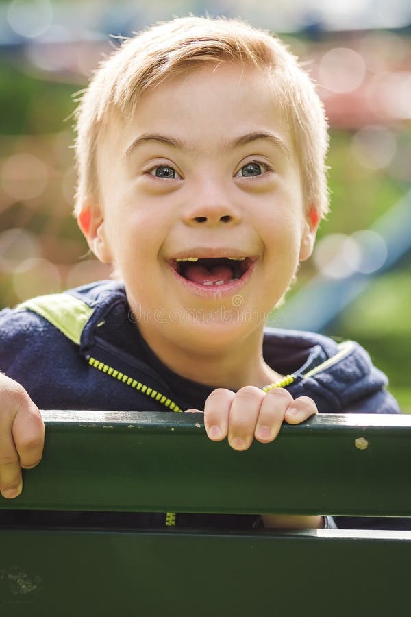 Portrait of a Little Boy with Down Syndrome while Playing in a Park Sit ...