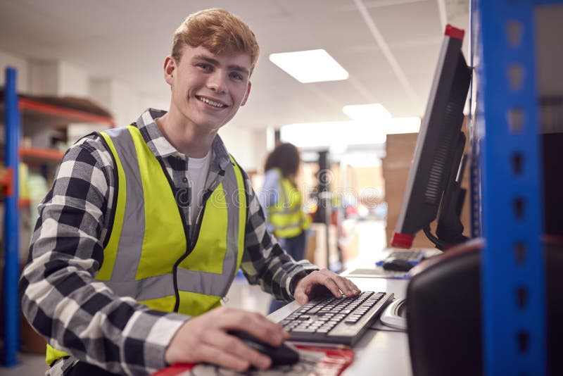 Portrait of Male Intern Working in Busy Modern Warehouse on Computer ...