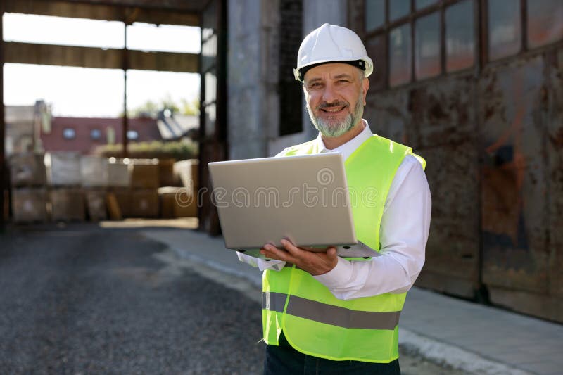 Portrait of the Man Builder in Helmet and Vest Using Wireless Laptop ...