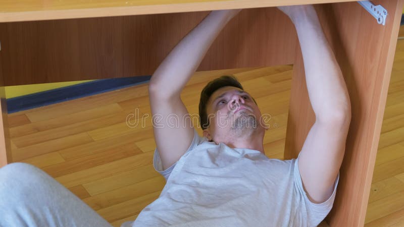 Portrait Of Man Collecting Parts Of Computer Table Screwing Lying Under Table Stock Video