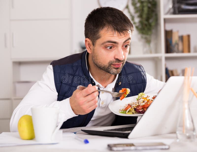 Portrait of Man Eating Vegetable Salad at Table with Laptop Stock Photo ...