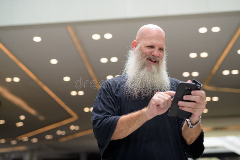 Happy Mature Handsome Bald Bearded Man Using Phone in the City Outdoors ... Happy Mature Handsome Bald Bearded Man Using Phone in the City Outdoors ...