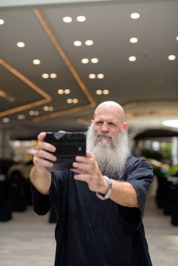 Mature Handsome Bald Bearded Man Taking Selfie in the City Outdoors ... Mature Handsome Bald Bearded Man Taking Selfie in the City Outdoors ...