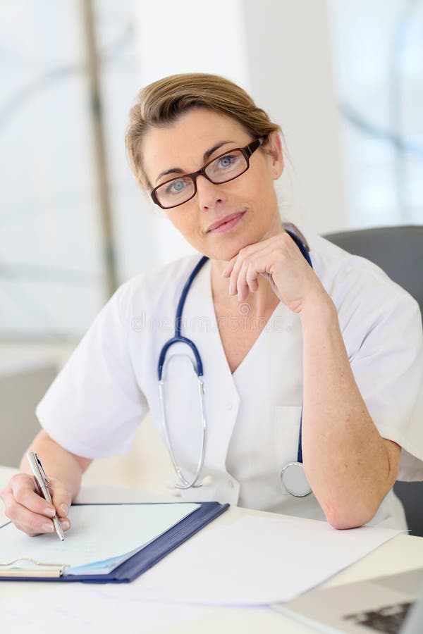 Portrait of Mature Nurse at Desk Stock Photo - Image of blond, cheerful ...