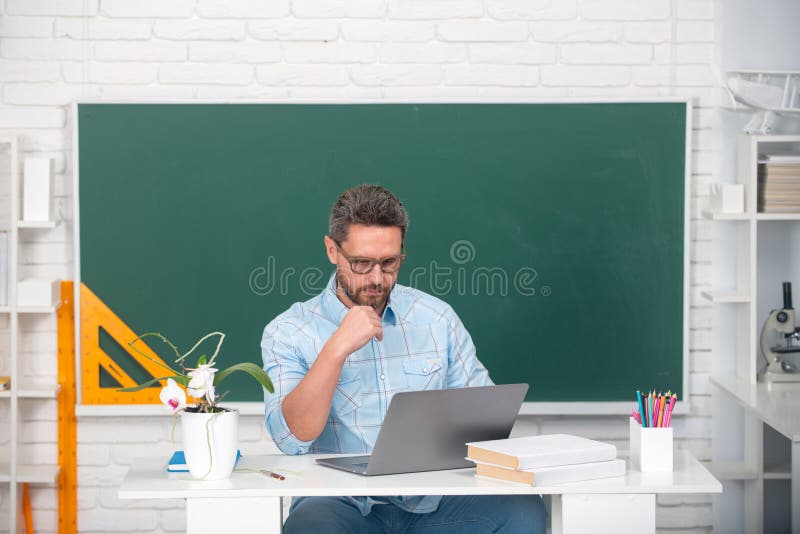 Portrait of Mature Teacher or Tutor Professor Working at Table in ...