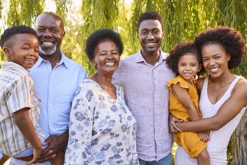 Portrait of Multi-Generation Family Standing in Garden Smiling at ...