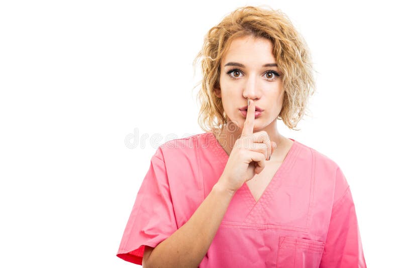 Portrait Of Nurse Wearing Pink Scrub Making Silence Gesture Stock Image