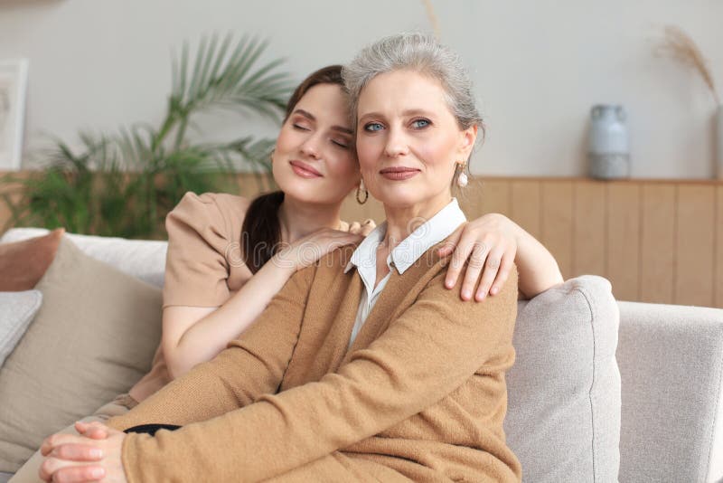 Portrait Of Old Mother And Mature Daughter Hugging At Home Happy
