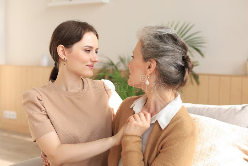 Portrait Of Old Mother And Mature Daughter Hugging At Home Happy