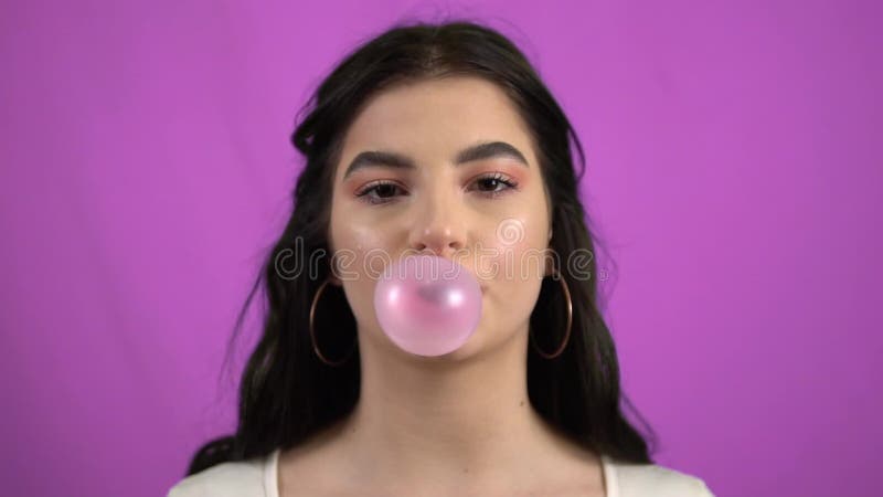 Girl Blowing Big Pink Bubble Gum Chewing On Purple Background Stock