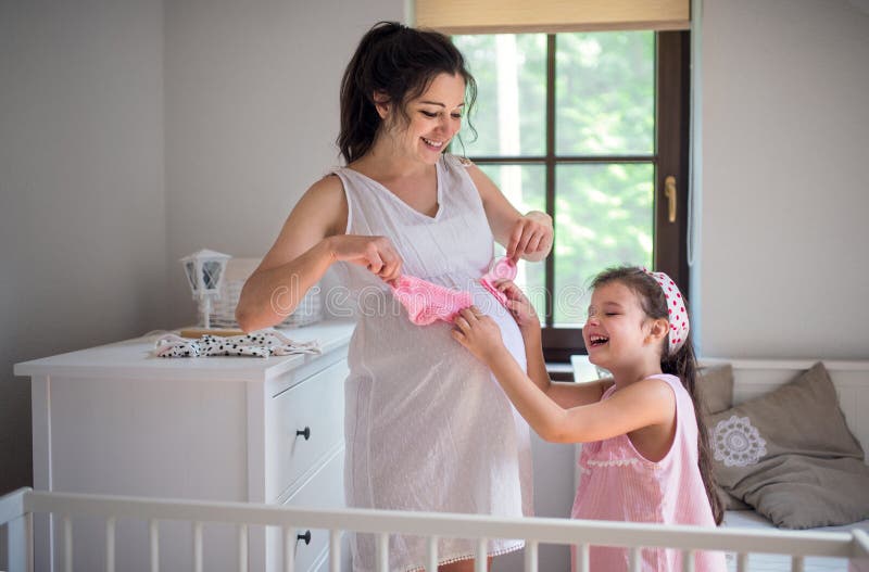 Portrait Of Pregnant Woman With Small Daughter Indoors At Home Stock