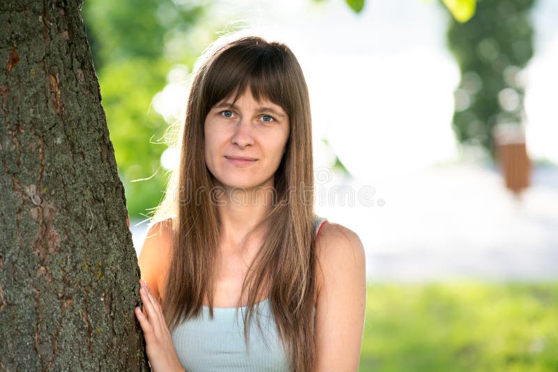 Portrait Of Pretty Young Woman With Long Hair Standing Neat Tree Trunk