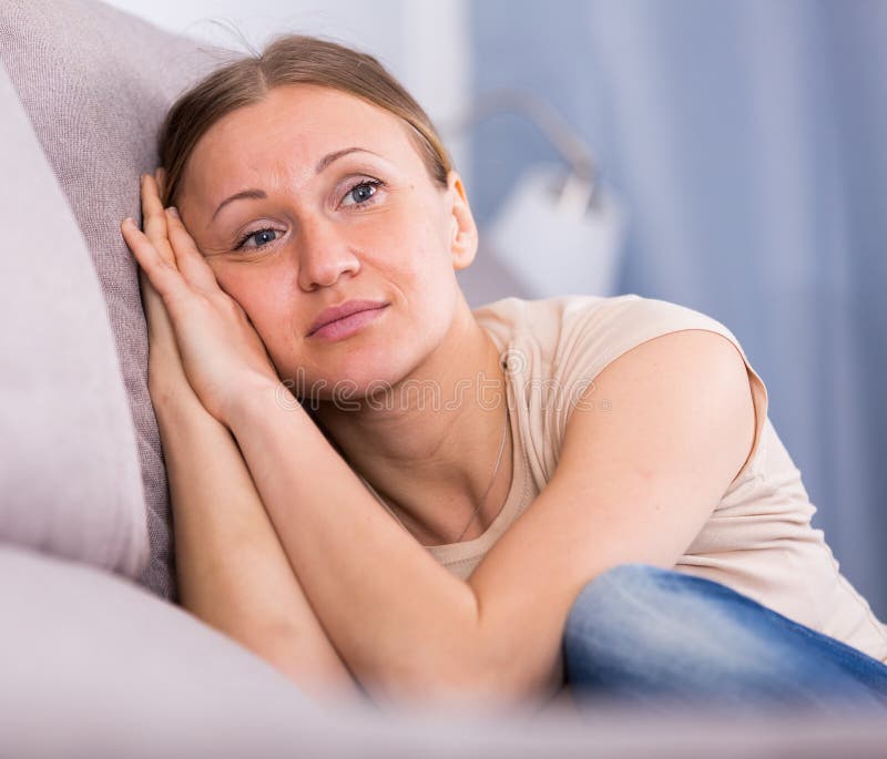 Sad woman sitting on sofa stock photo. Image of relationship - 225211212