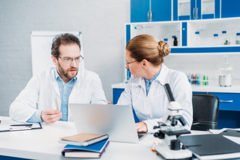 Portrait of Scientists in Lab Coats and Eyeglasses Working Together at ...
