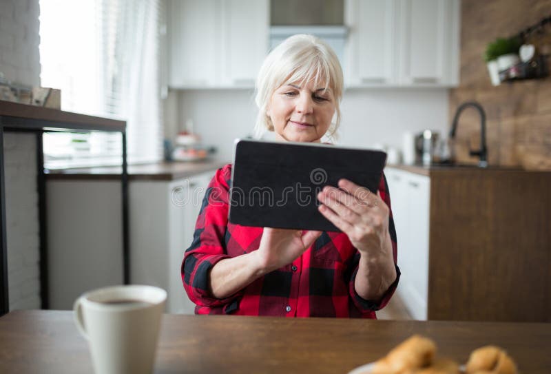 Senior Lady Using Tablet at Kitchen Table Stock Photo - Image of female ...