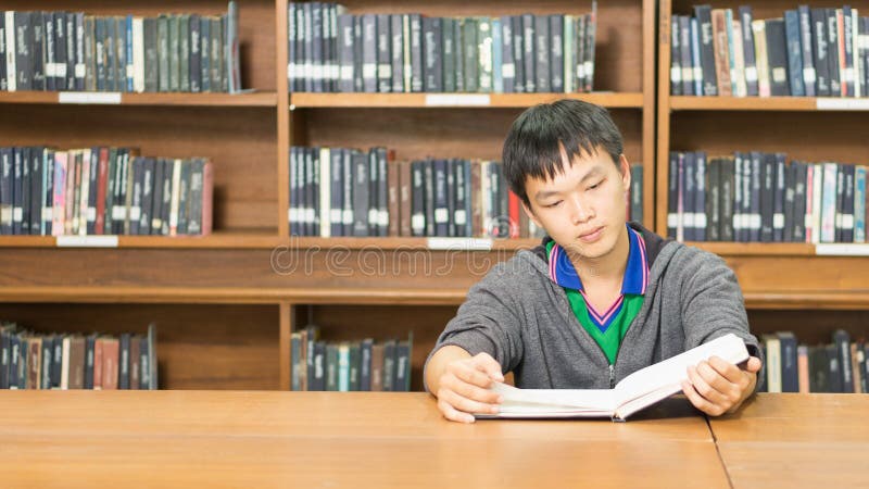 Portrait Of A Serious Young Student Reading A Book In A Library Stock ...
