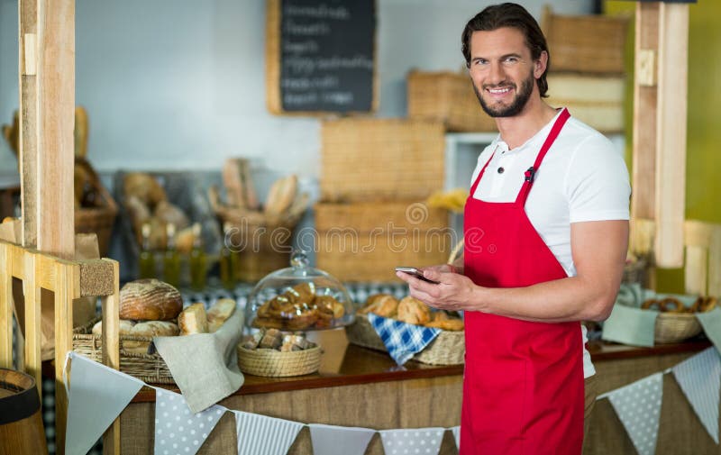 Portrait of Smiling Bakery Staff Using Mobile Phone at Counter Stock ...