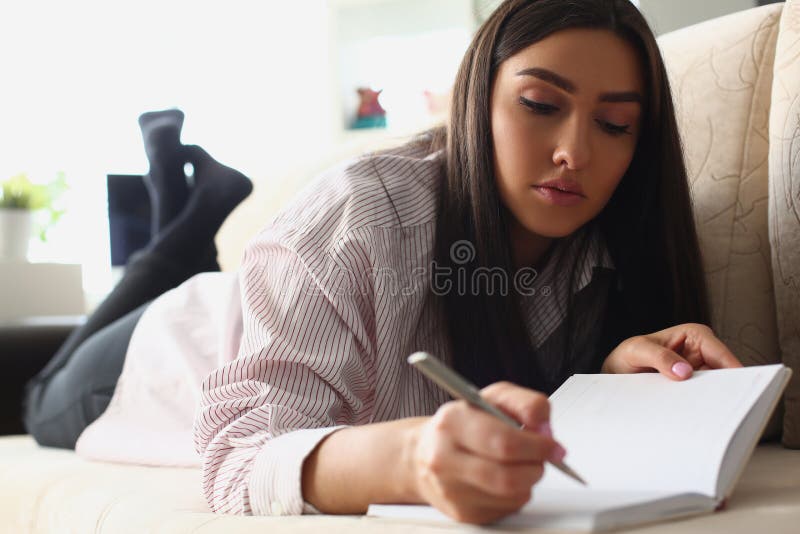 Portrait of Smiling Beautiful Woman Writing Notes in Notebook Lying on ...