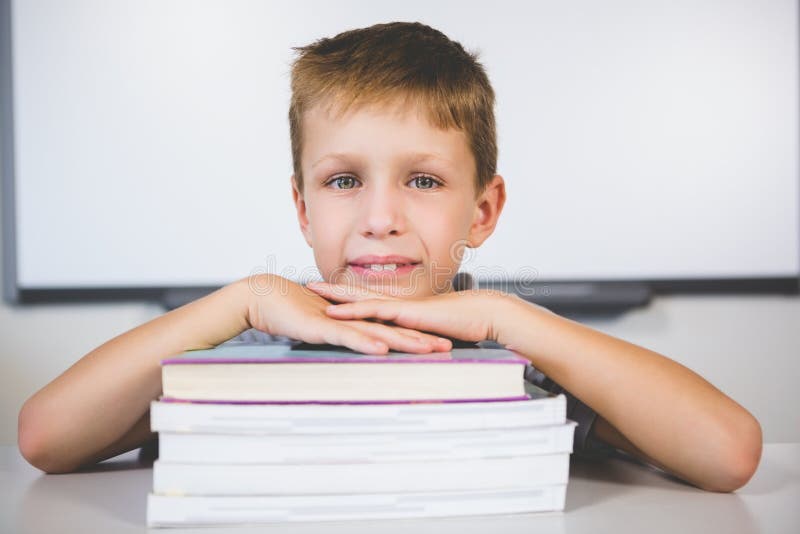 Portrait of Smiling Boy Leaning on Stack of Books in Class Room Stock ...