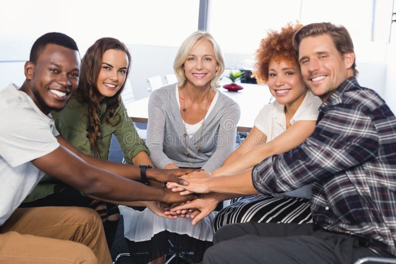 Portrait of Smiling Business People Stacking Hands while Sitting on ...