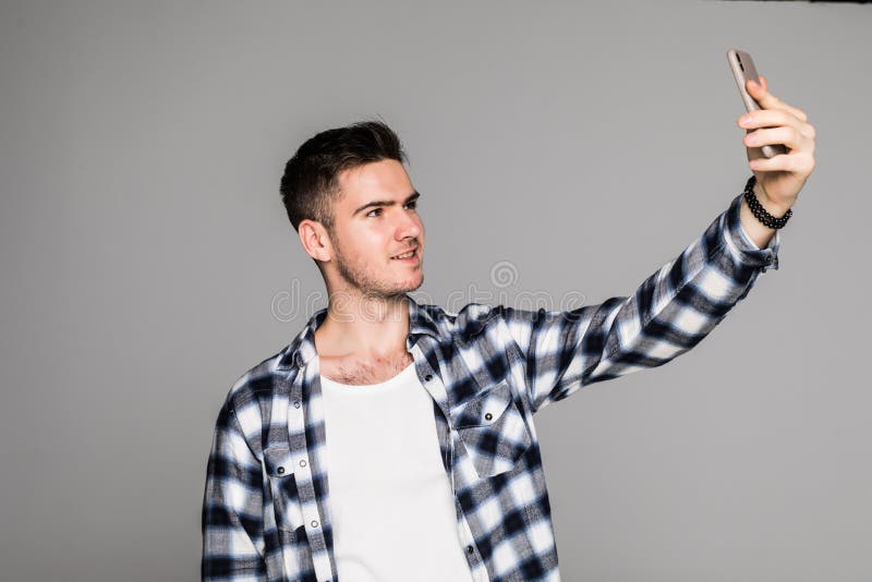 Portrait of a Smiling Casual Man Taking Selfie Over Gray Background ... Portrait of a Smiling Casual Man Taking Selfie Over Gray Background ...