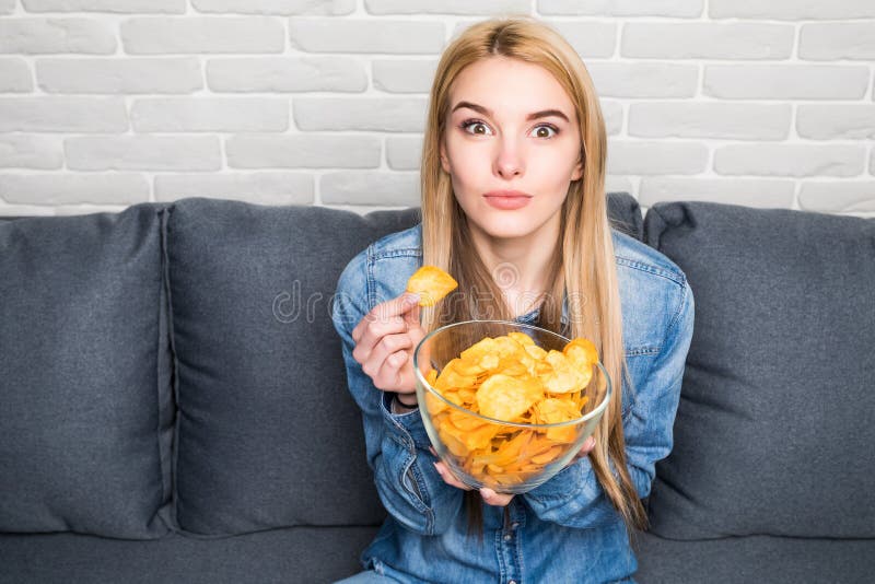 Portrait of Smiling Girl Eating Chips at Home on Sofa Stock Photo ...