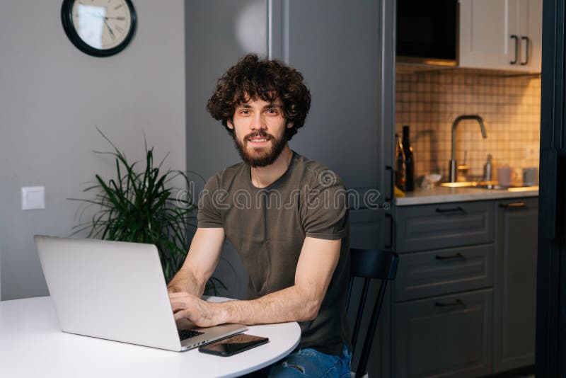 Portrait of Smiling Handsome Young Man Using Laptop Sitting at Table in ...