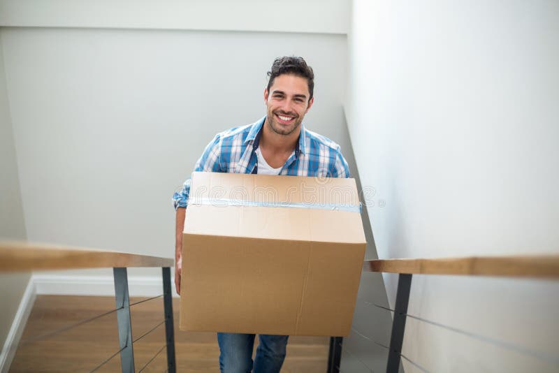 Portrait of Smiling Man Holding Cardboard Box while Climbing Steps ...