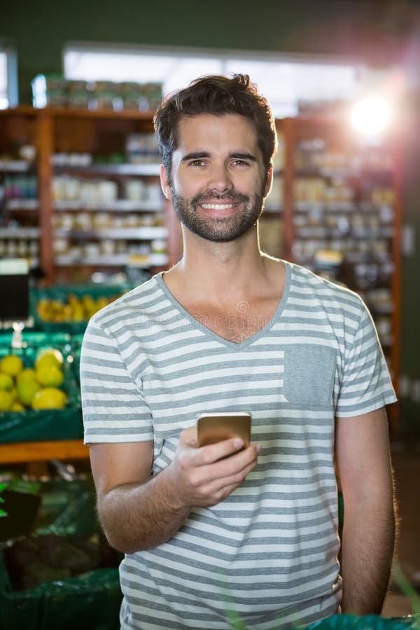Portrait of Smiling Man Using His Phone in the Organic Section Stock ...