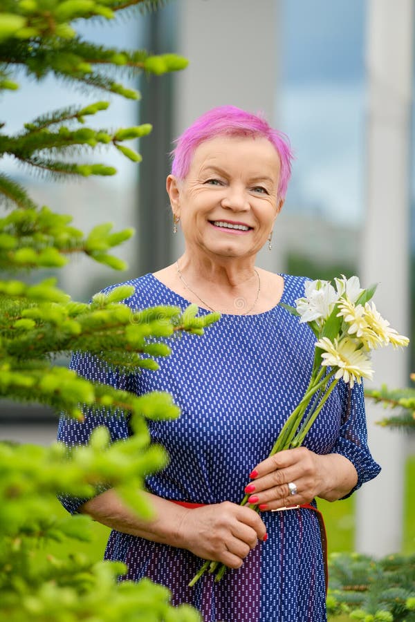 Portrait of Smiling Mature Woman Standing Near Fir-tree with Spring ... Portrait of Smiling Mature Woman Standing Near Fir-tree with Spring ...