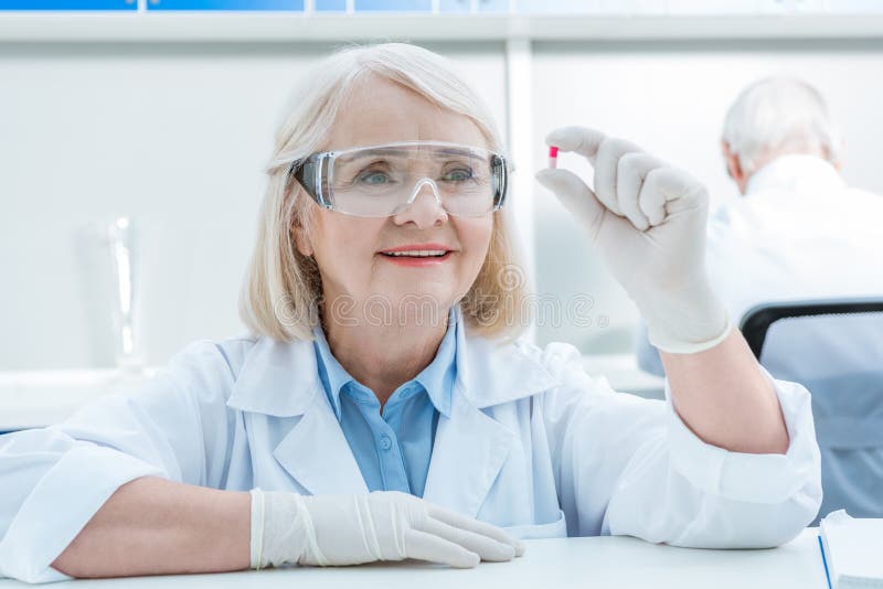 Portrait of Smiling Senior Woman Scientist Analyzing Pill in Hand Stock ...