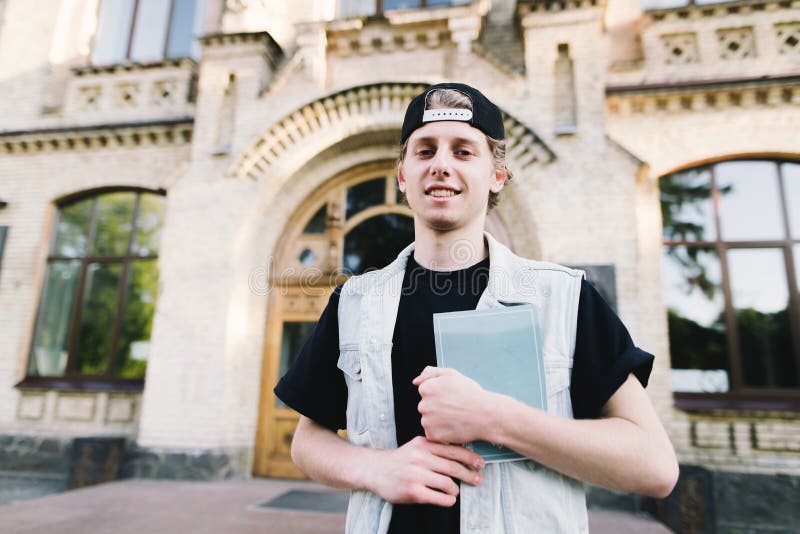 Portrait of a Smiling Student in a Cap and Notebook in His Hands ...
