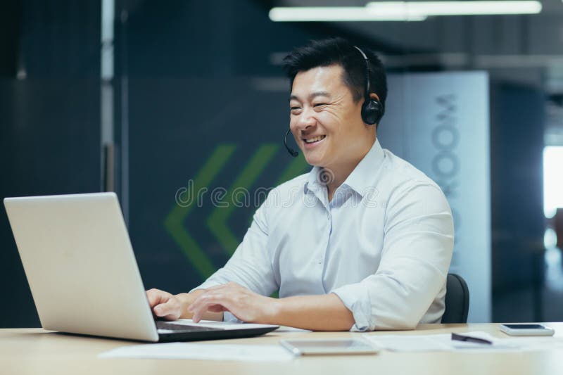 Portrait of a Smiling Young Asian Man Working in the Office at a Laptop ...