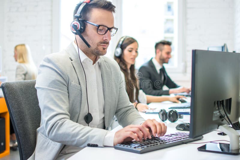 Portrait of a Smiling Young Man with Headset Using Computer in the ...