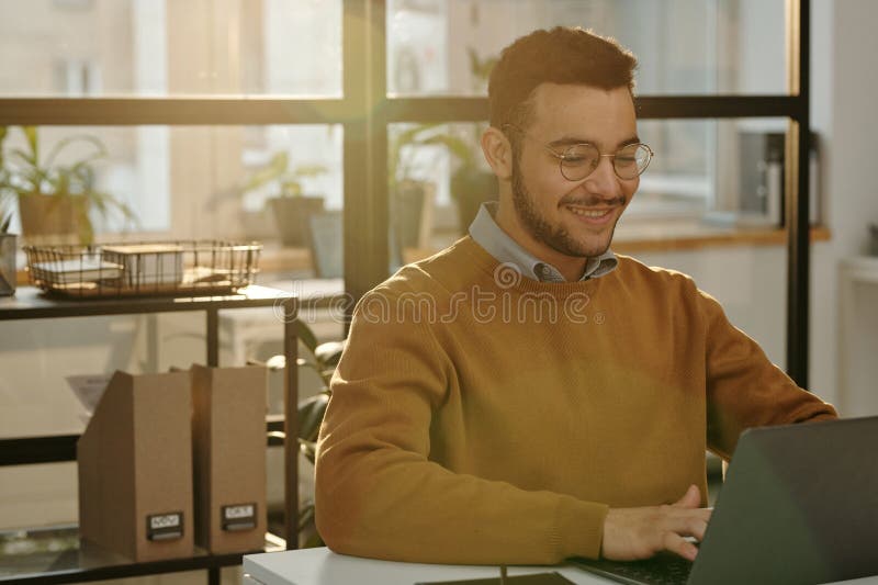 Smiling Man Using Computer in Office Lit by Sunlight Stock Photo ...