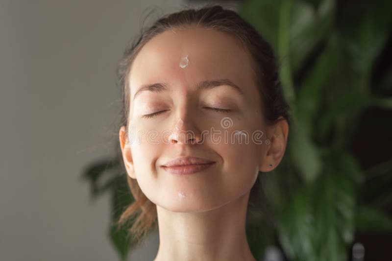 Portrait Of Smiling Young Woman Applying Some Moisturizing Face Cream
