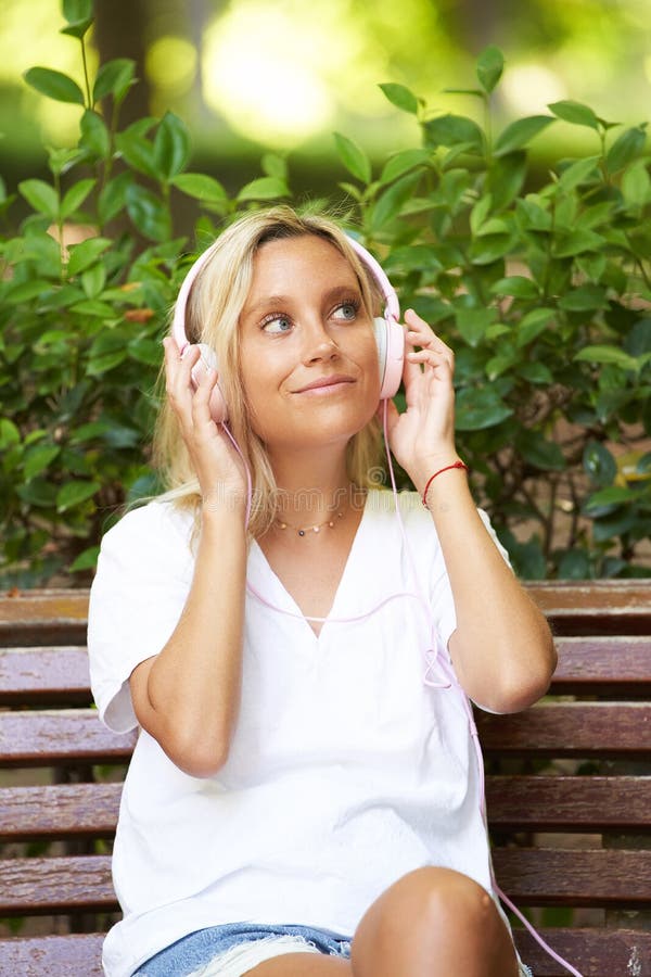 Portrait Of A Smiling Young Woman Sitting On A Bench In A Natural Park