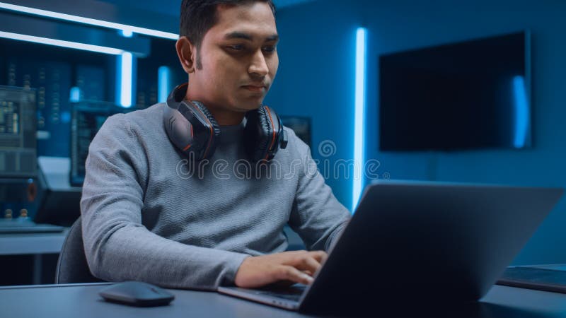 Portrait Of Software Developer Hacker Programmer Sitting At His Desk And Working On Laptop