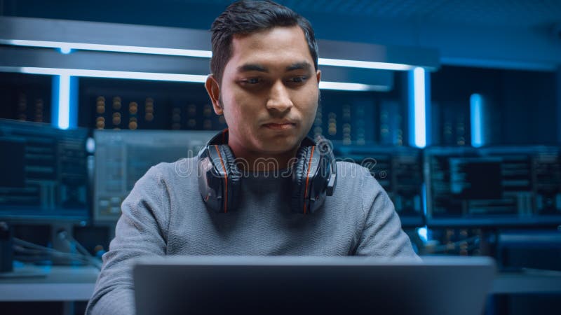 Portrait Of Software Developer Hacker Programmer Sitting At His Desk And Working On Laptop