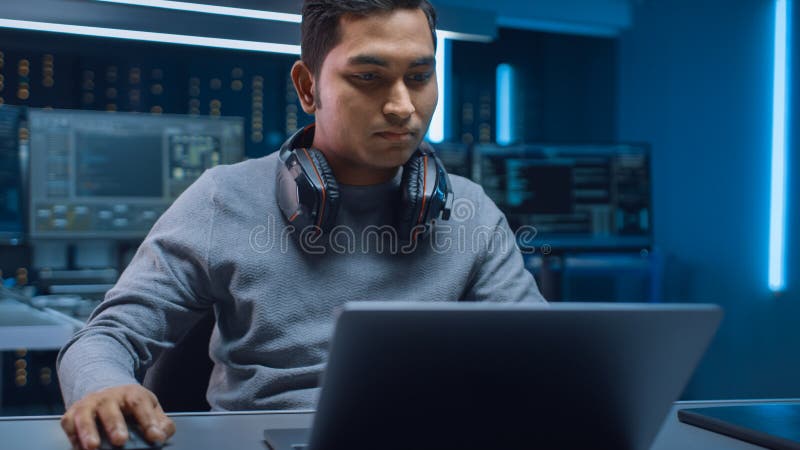 Portrait Of Software Developer Hacker Programmer Sitting At His Desk And Working On Laptop