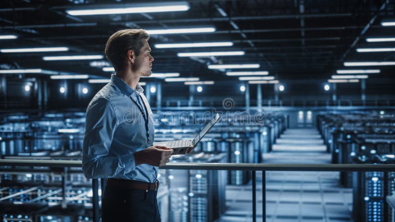 Portrait of it Specialist Uses Laptop in Data Center. Server Farm Cloud Computing Facility with ...